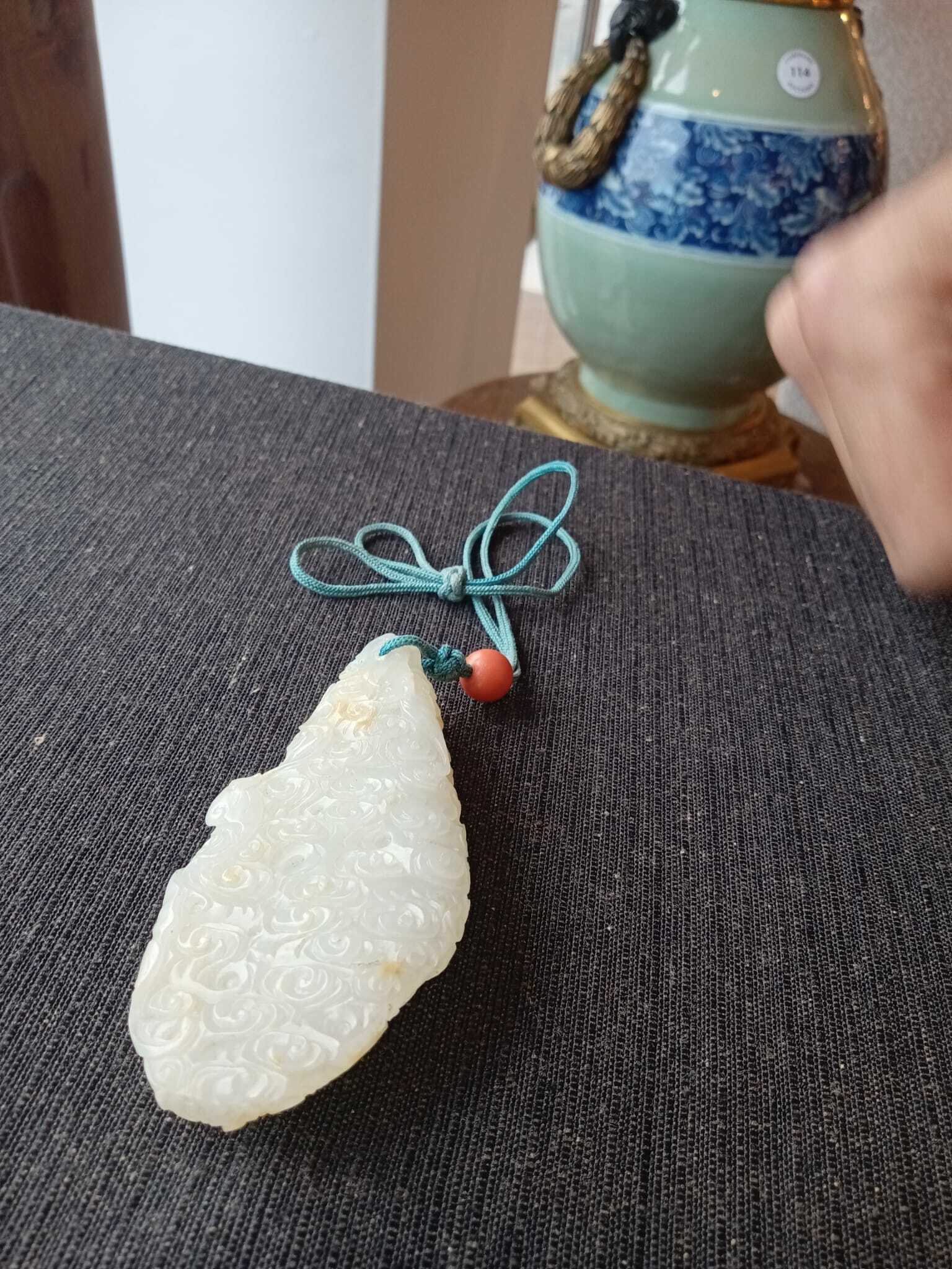 A Chinese jade pendant with bats surrounding a 'precious umbrella ...